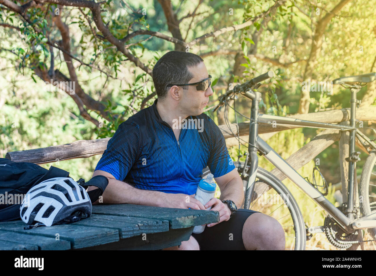 male cyclist resting and drinking isotonic drink after training with ...