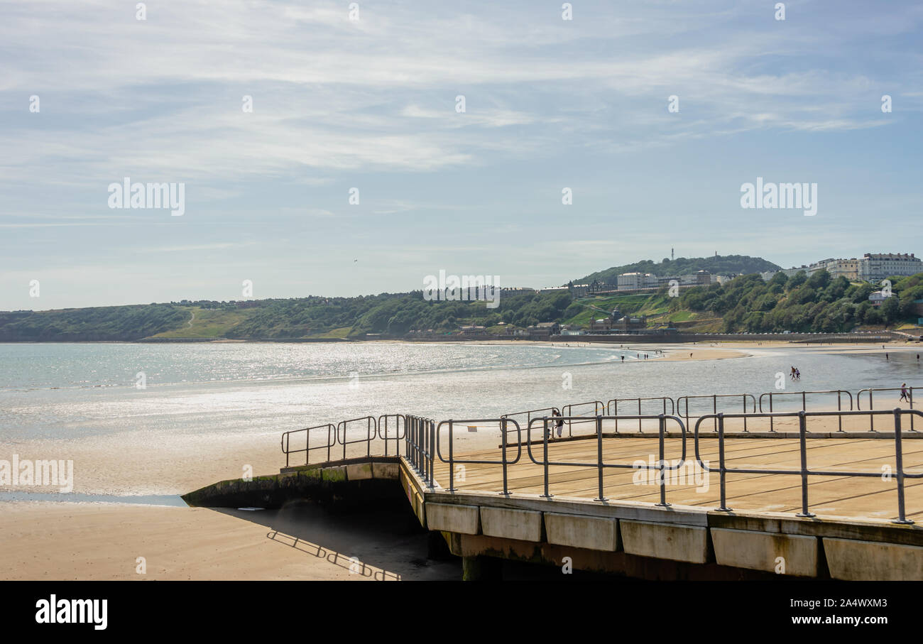 A lifeboat ramp leads down to Scarborough beach late summer. A headland ...