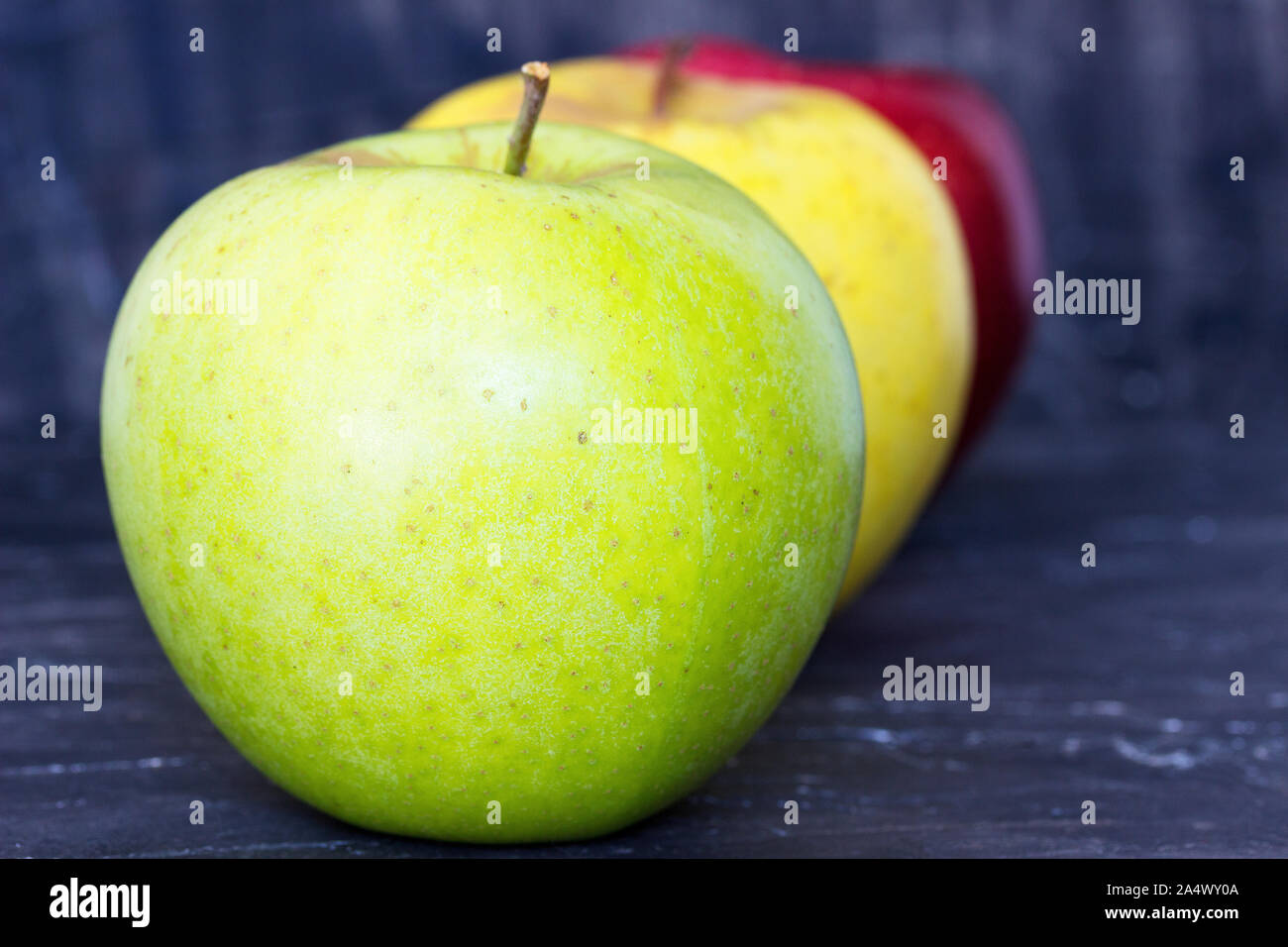 Green ,yellow and red apples on a dark wooden base Stock Photo - Alamy