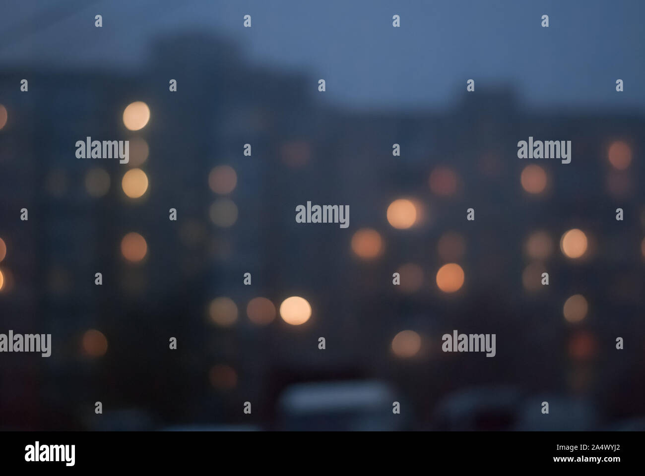 Blurred background of evening cityscape with luminous windows in houses ...