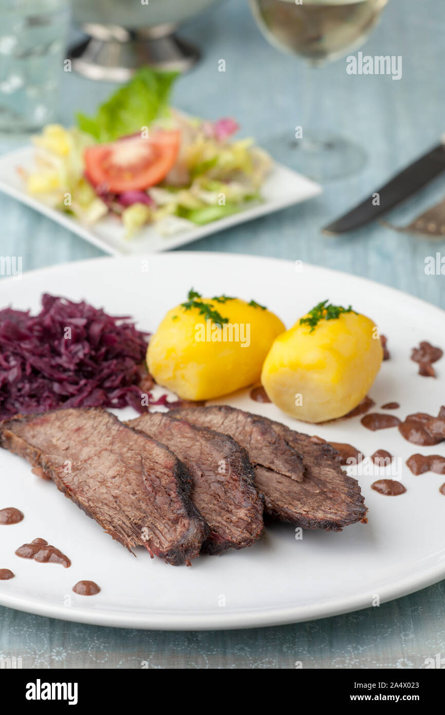 german sauerbraten with red cabbage on a plate Stock Photo - Alamy