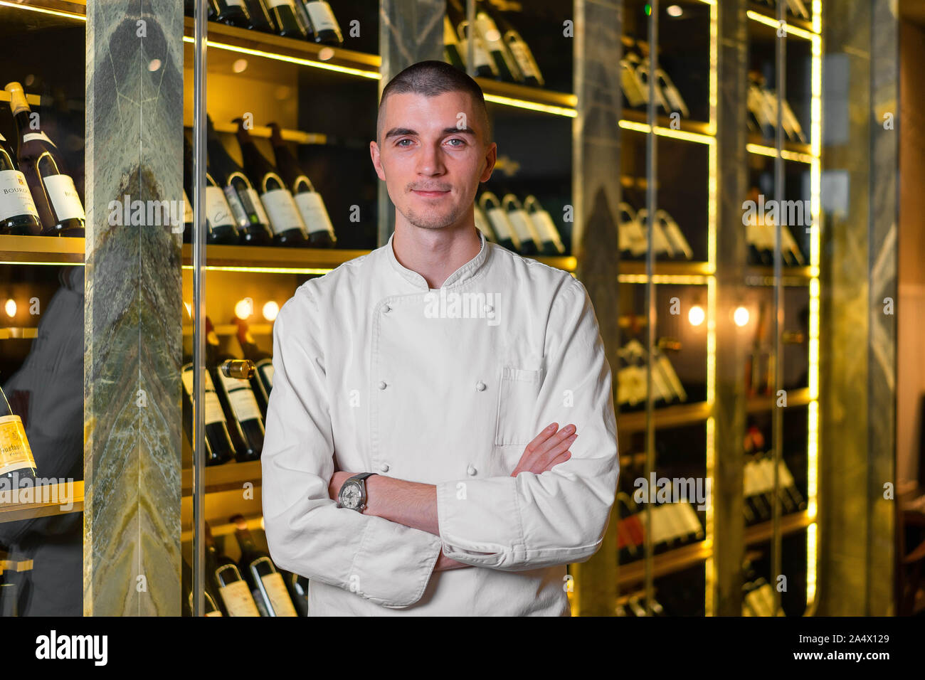 Young handsome cook chief posing in modern restaurant interior on ...