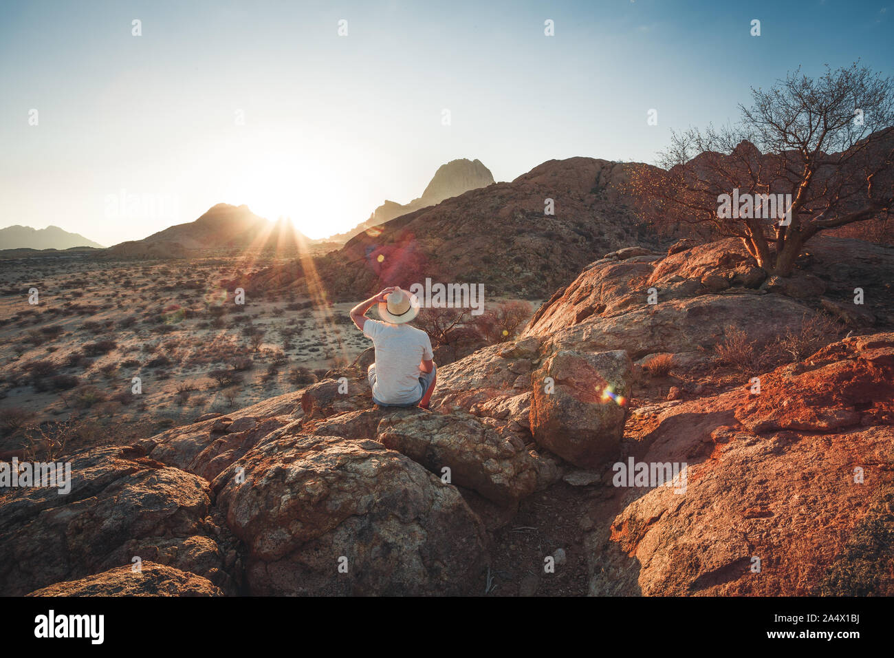 young man holding his hat while watching at Spitzkoppe in Namibia Stock ...