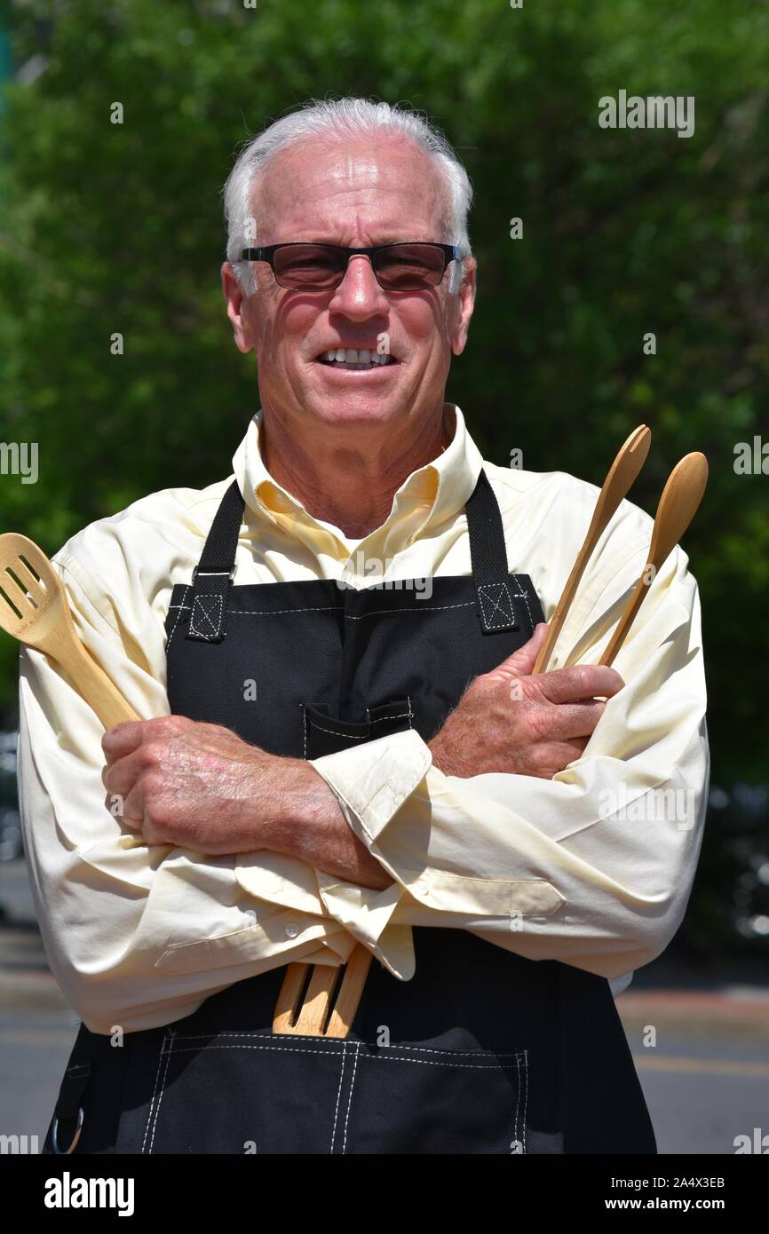 Happy Male Cook Wearing Apron With Kitchen Utensils Stock Photo - Alamy