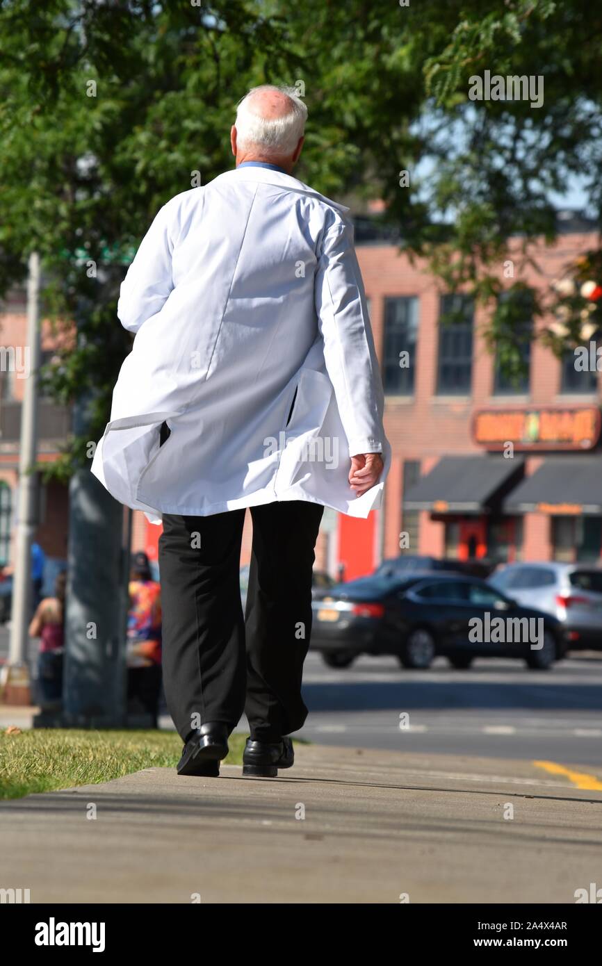 Senior Balding Male Doctor Walking On Sidewalk Stock Photo - Alamy