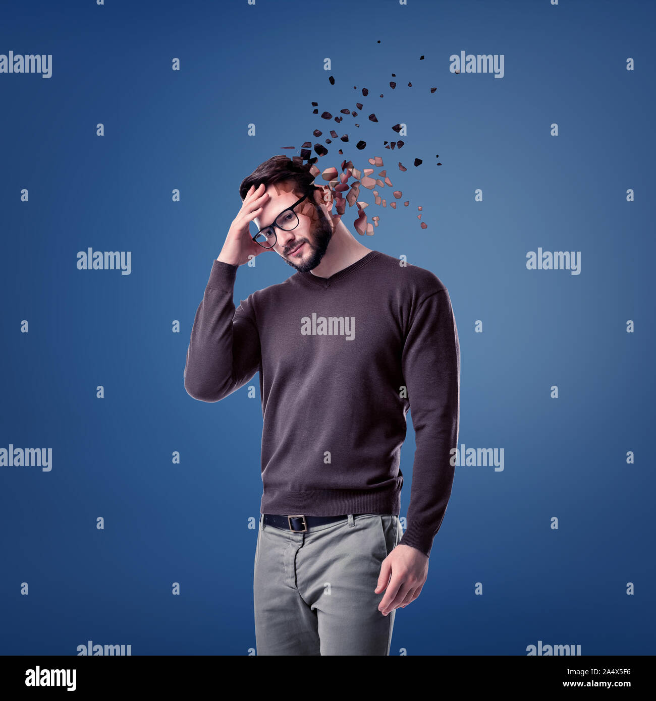 A young bearded man in glasses stands with his head on his forehead ...