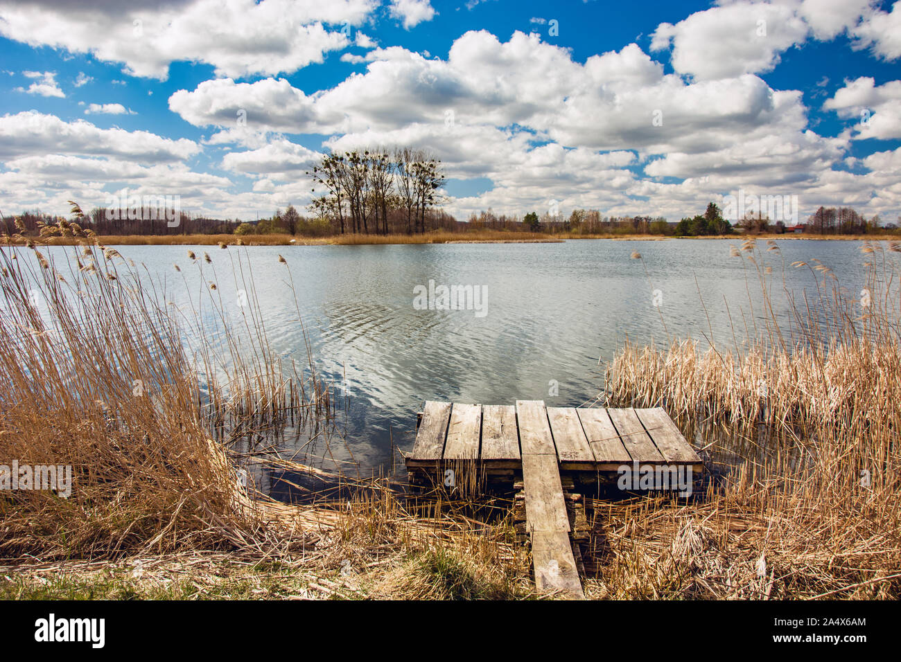 Wooden platform on the shore of the lake, white clouds on the sky Stock ...