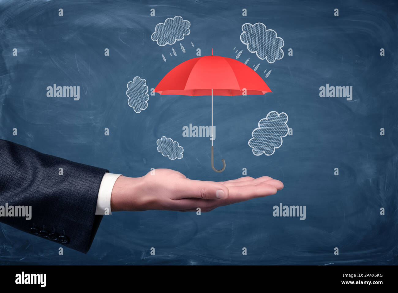 A businessman's hand turned up and a small red umbrella hovering above ...