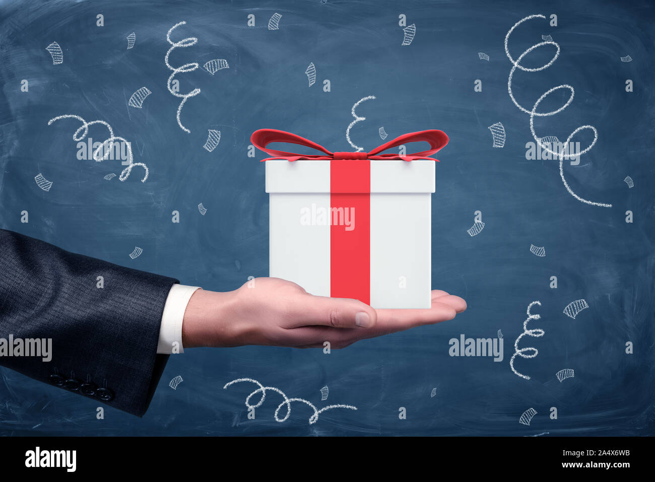 A businessman's hand turned up and a small gift box with a red bow ...