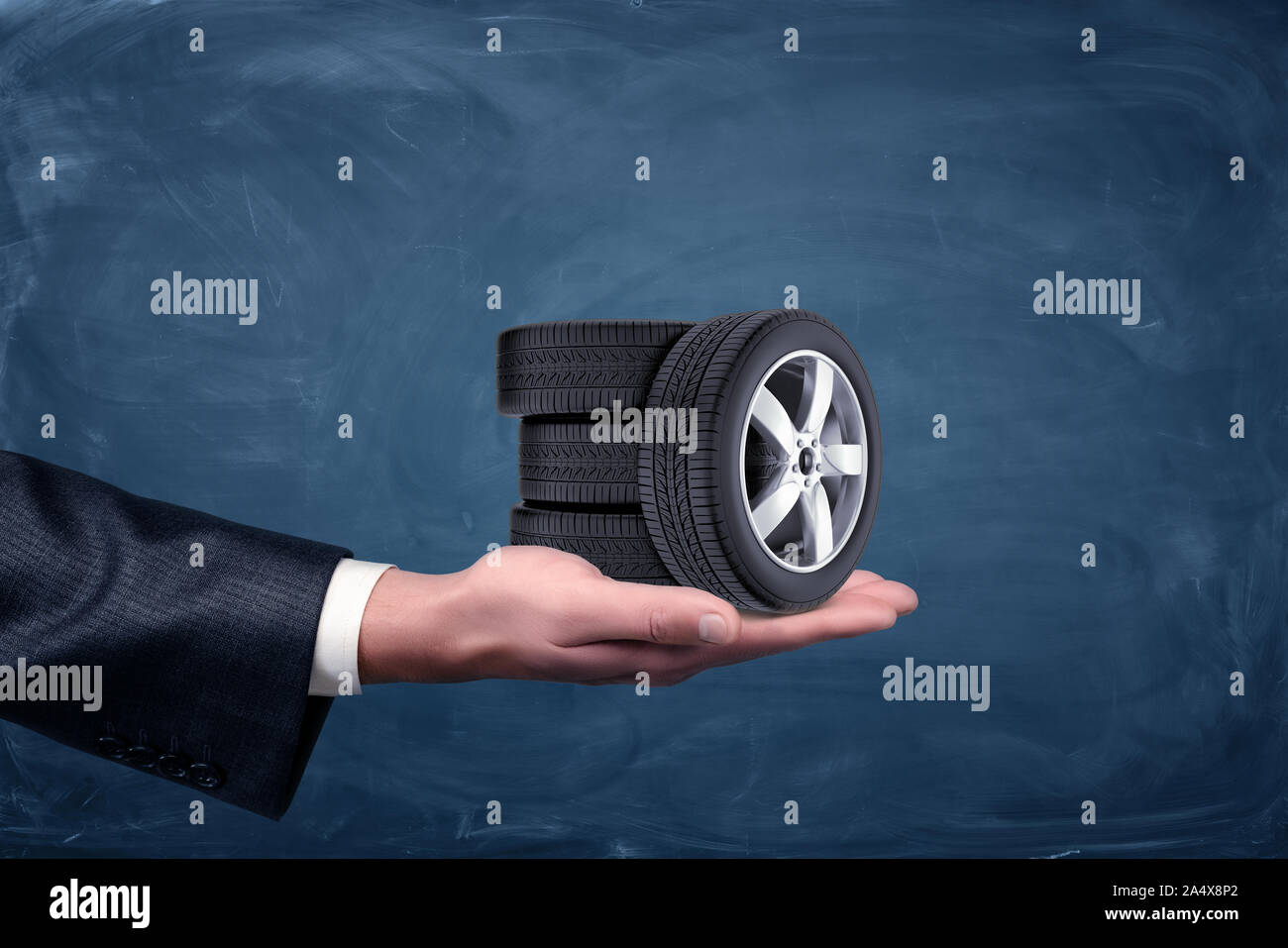 A businessman's hand on blue chalkboard background holding four tiny ...