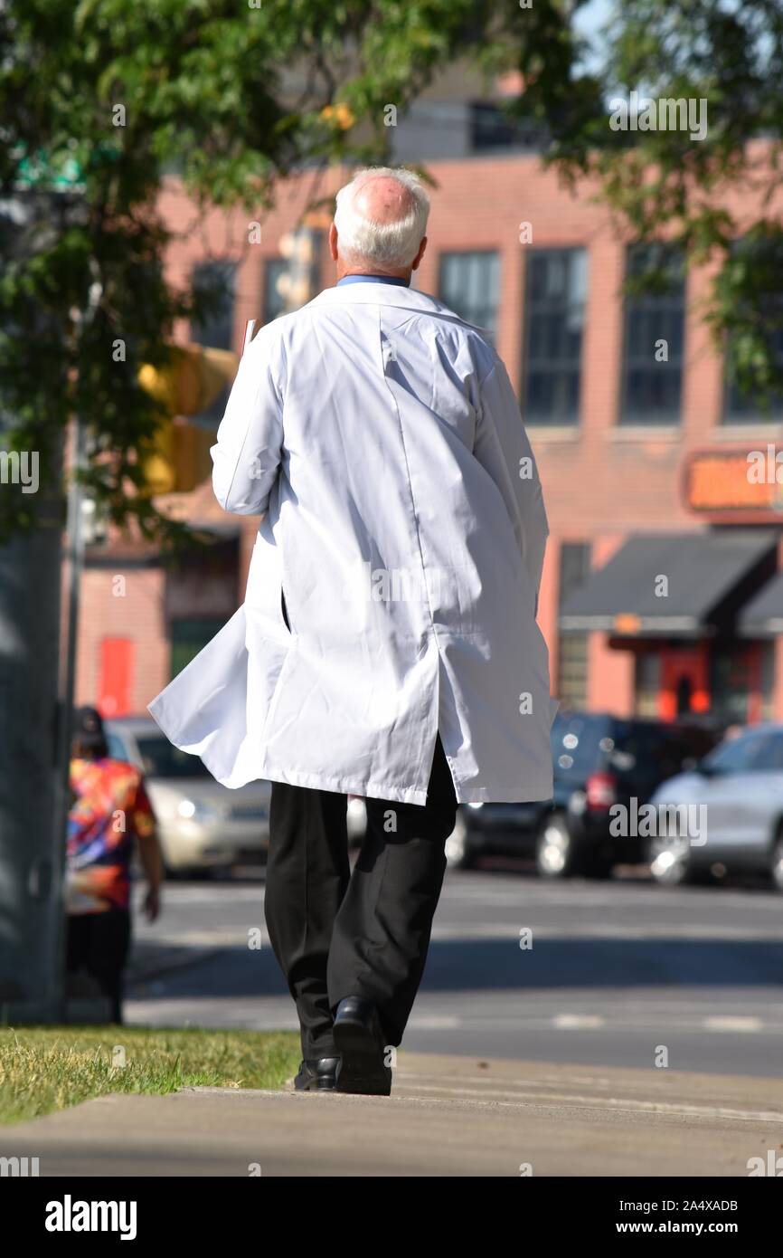 Senior Balding Male Doctor Walking On Sidewalk Stock Photo - Alamy