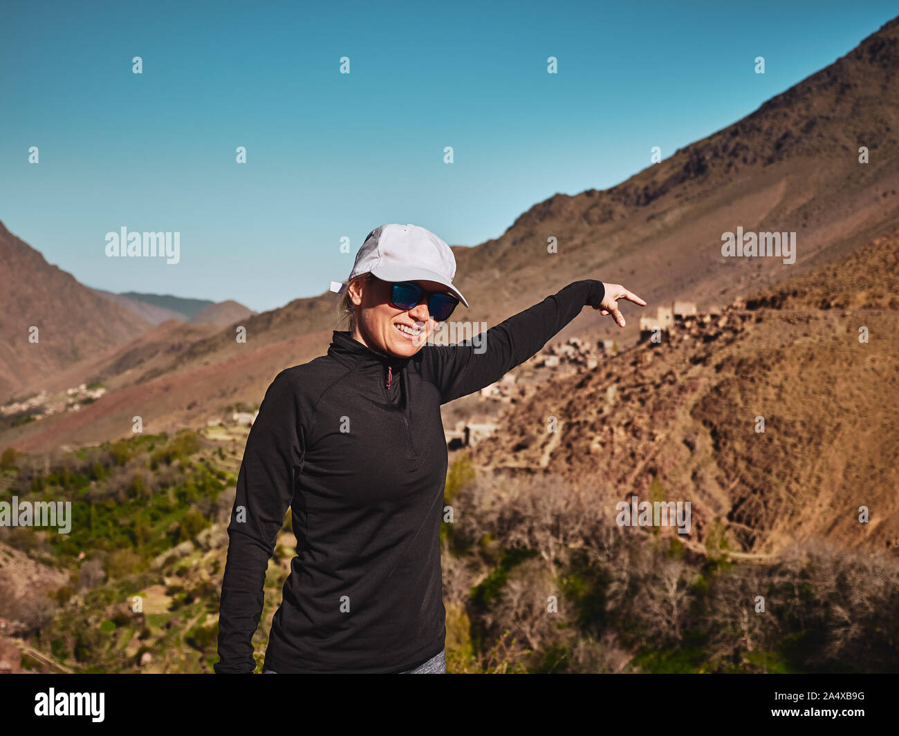 Smiling tourist girl pointing with her finger at a house in traditional ...