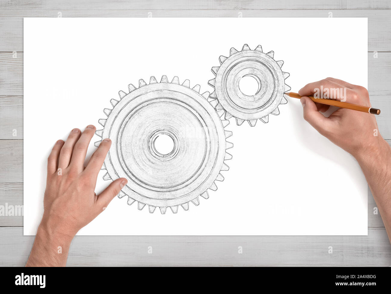 A first person view on male hands drawing two large spur gears on paper ...