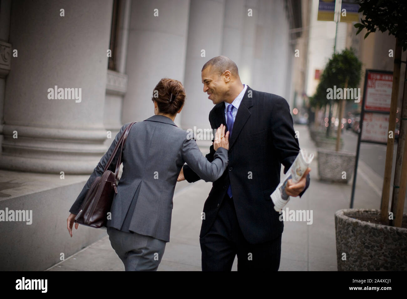 Mid-adult businessman laughing while being pushed aside by a female ...