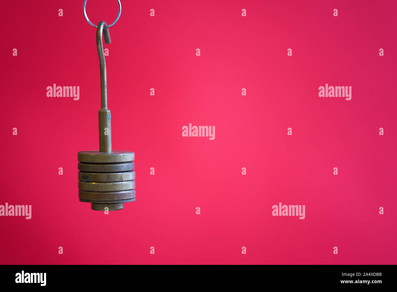 Masses hanging on a stretched spring isolated on a red background ...