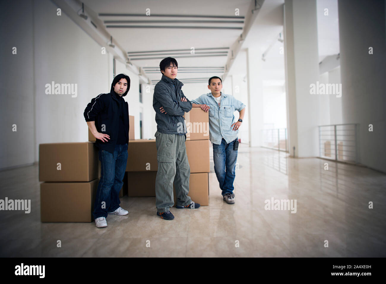 Portrait of three young men standing inside a large empty room Stock ...