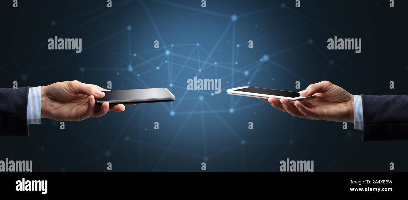 Close up of two hands holding smartphones to each other, wireless ...
