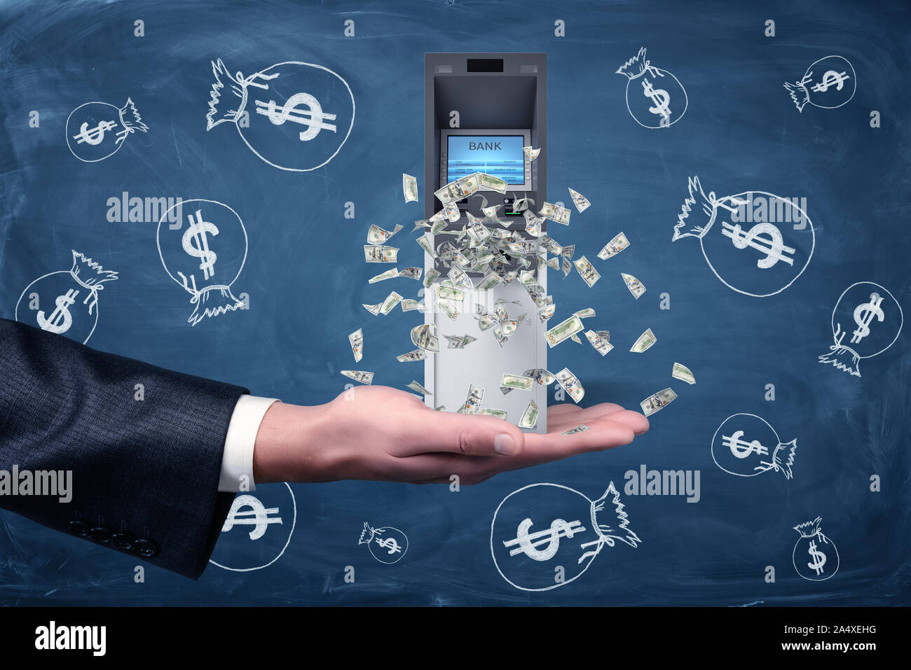 A businessman's hand holding a tiny bank ATM machine with dollar bills ...