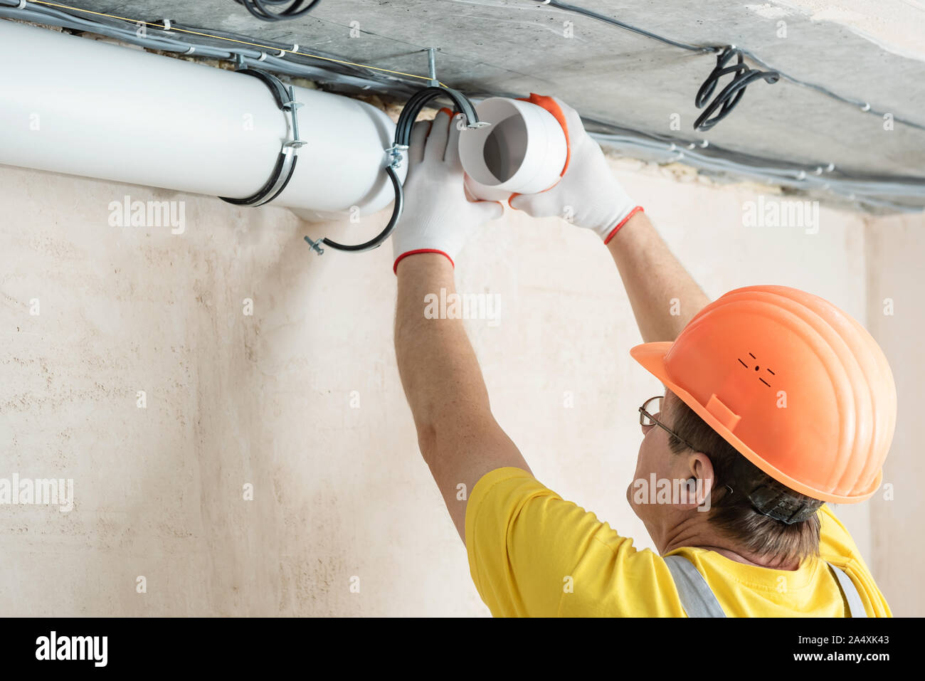 The worker is installing a ventilation system in the apartment Stock ...