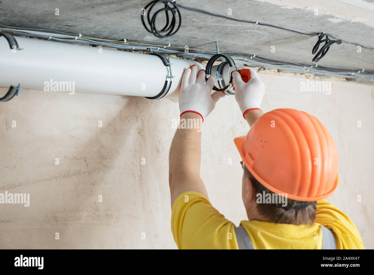 The worker is installing a ventilation system in the apartment Stock ...