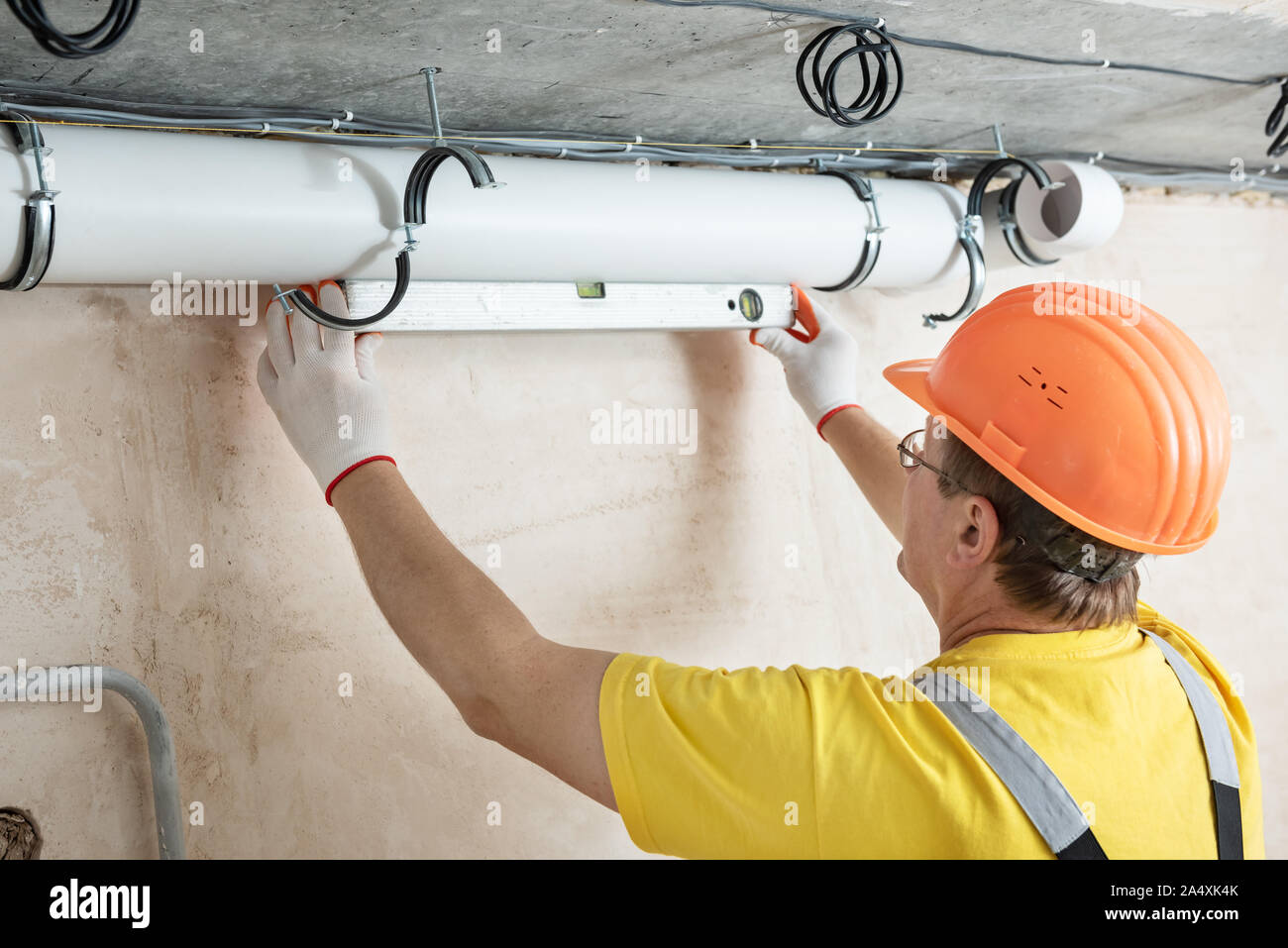 The worker is installing a ventilation system in the apartment Stock ...