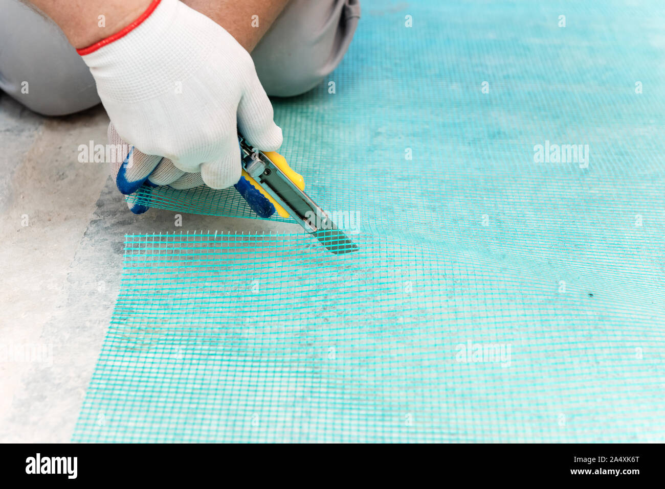 A worker is cutting off a piece of fiberglass mesh with a knife Stock ...