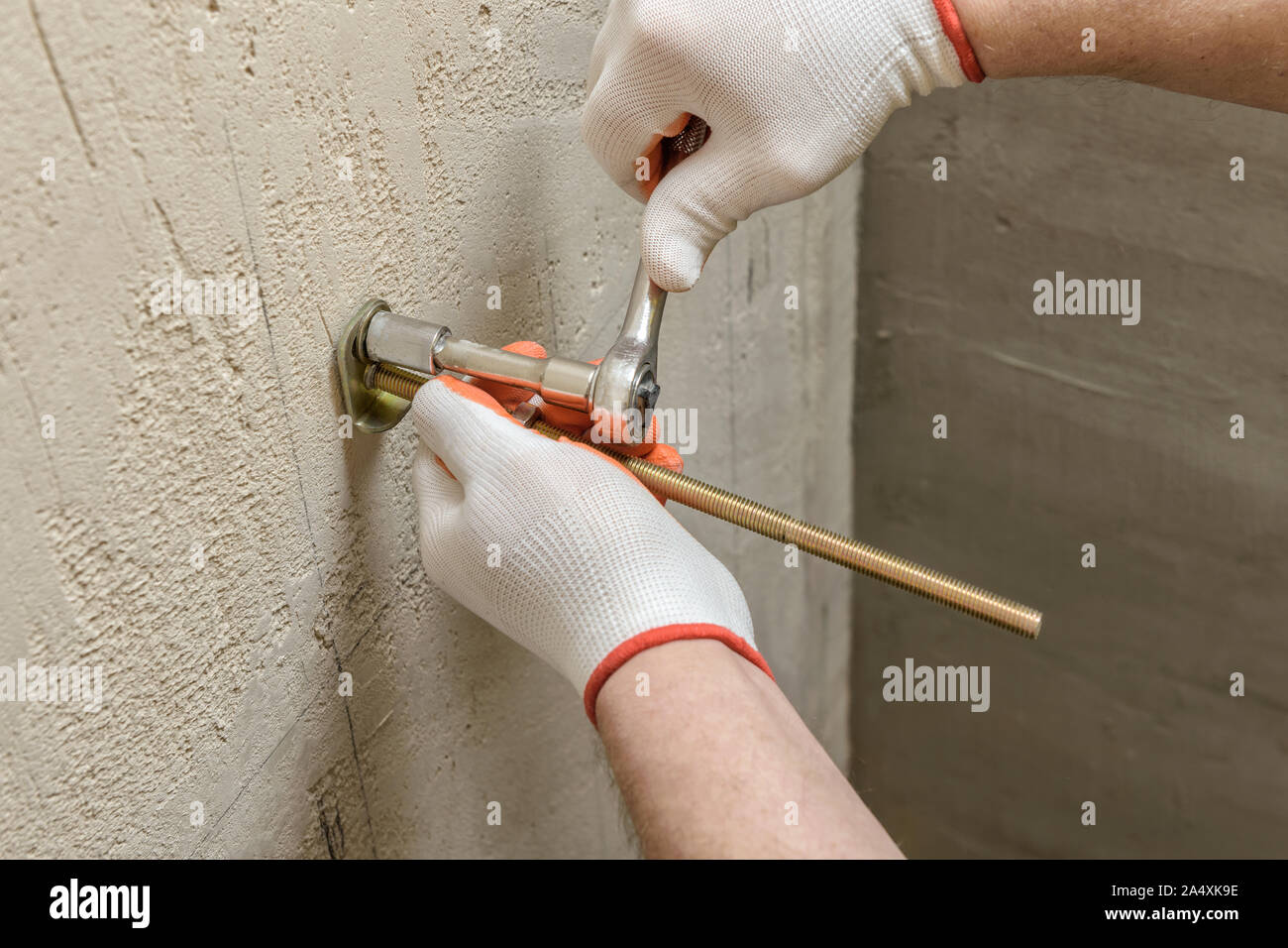 A worker is fixing up a wall of bolts. To further fasten a frame with a ...