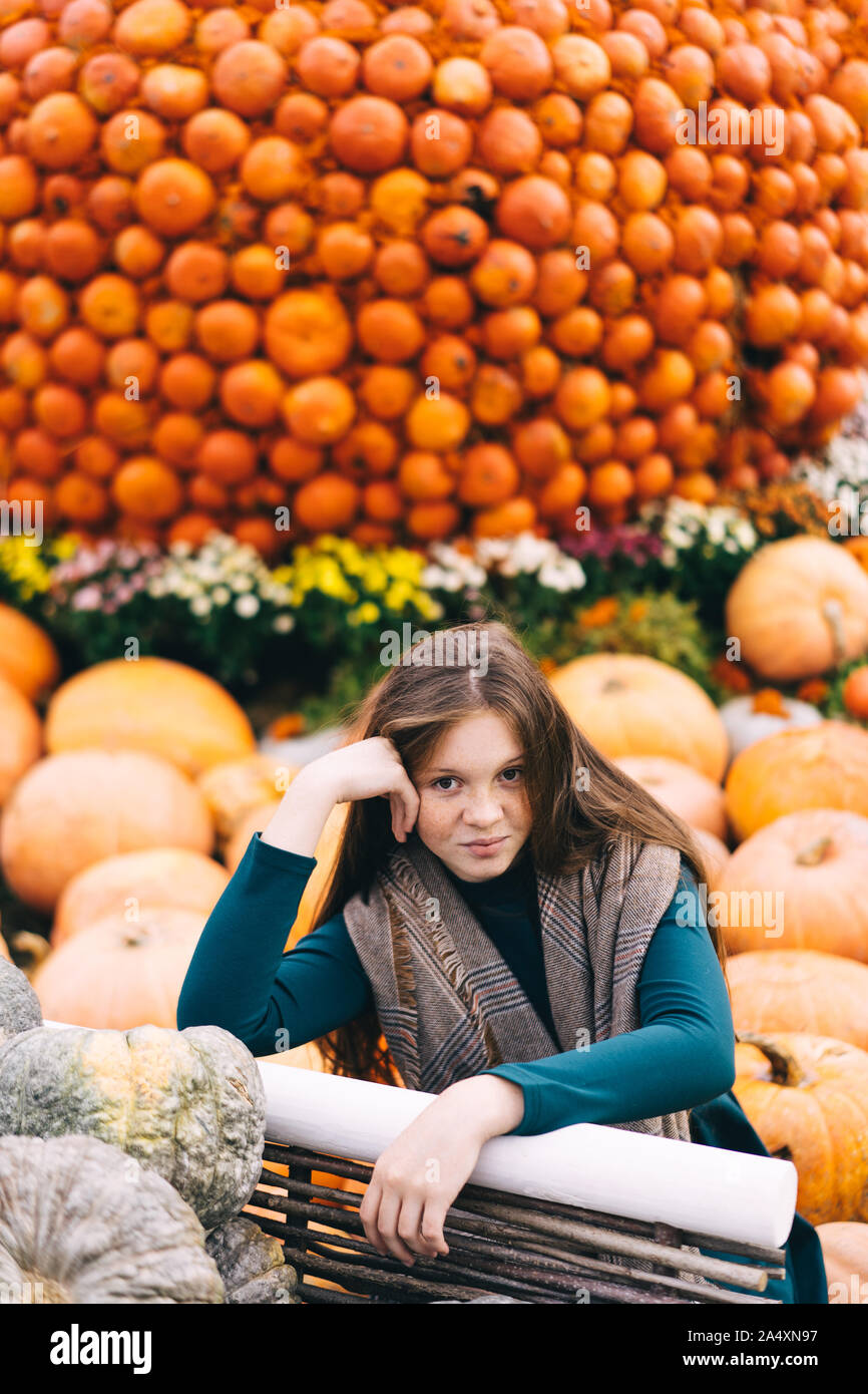 A red-haired teenage girl with freckles on face sits near a cart ...