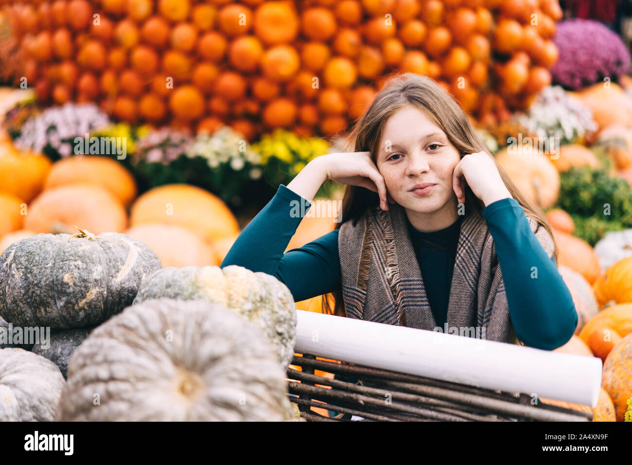 A red-haired teenage girl with freckles on face sits near a cart ...
