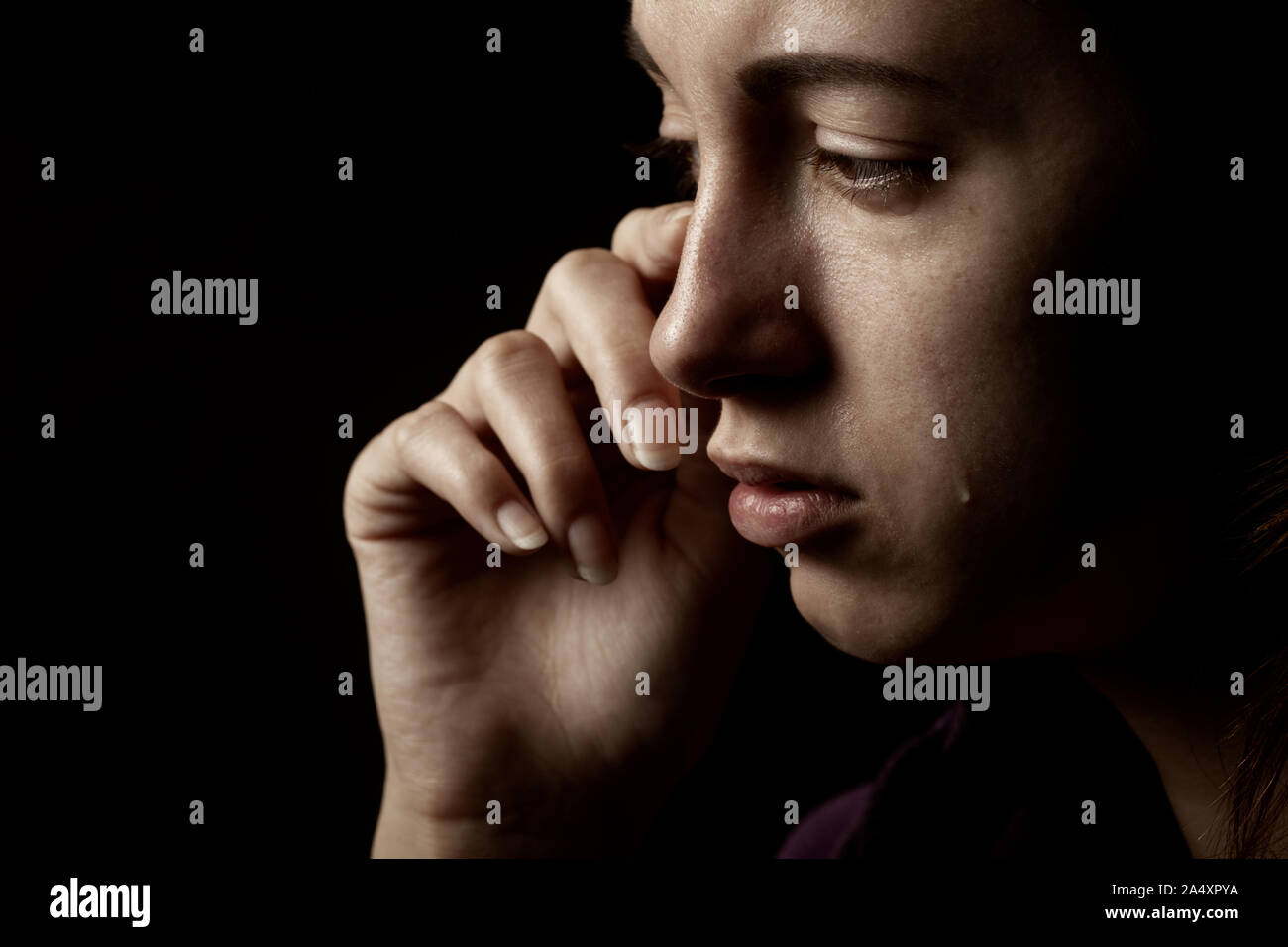 sad woman crying on black background, looking down, closeup portrait ...