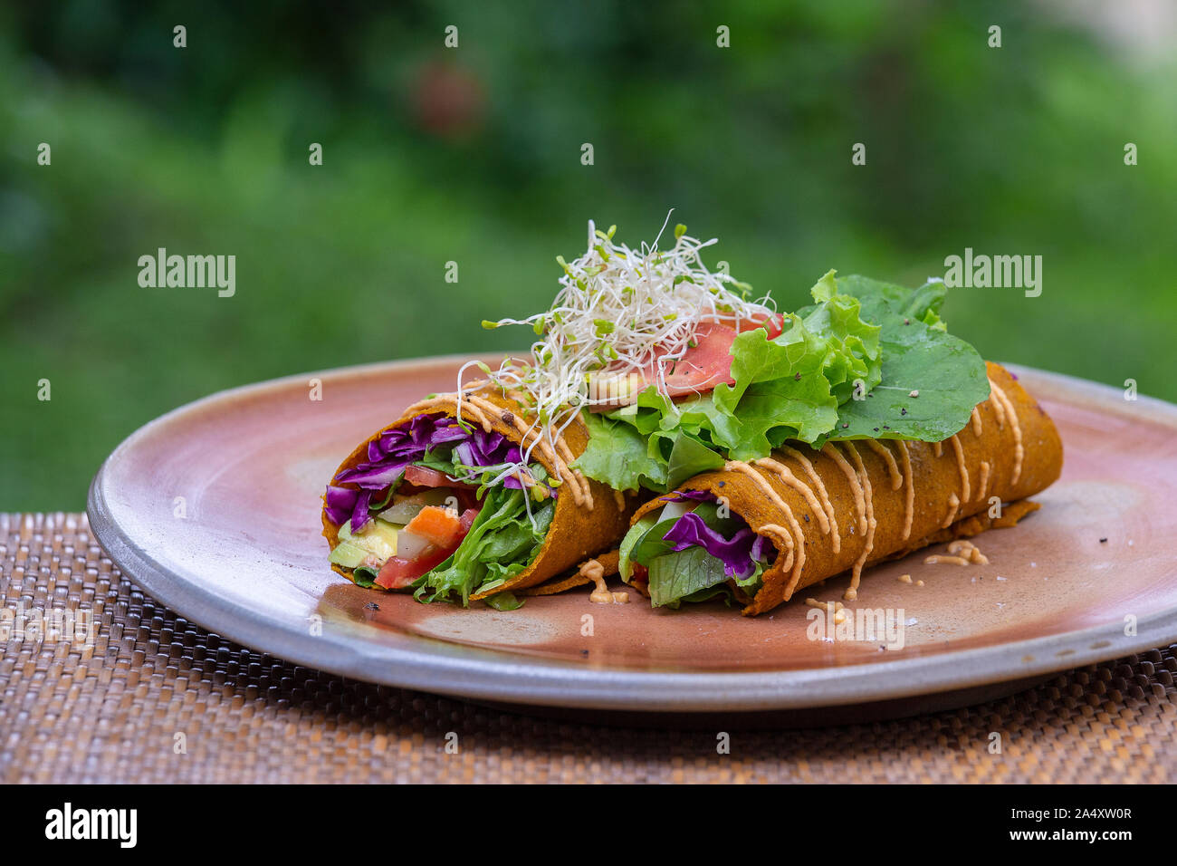 Raw vegan carrot and cumin wrap roll stuffed with shred lettuce, tomato ...