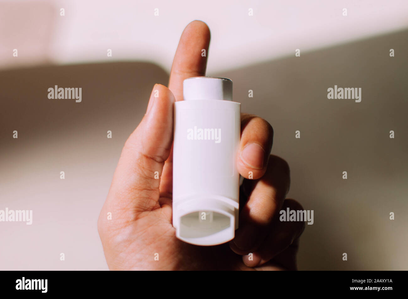 A young person is holding an asthma inhaler device Stock Photo - Alamy