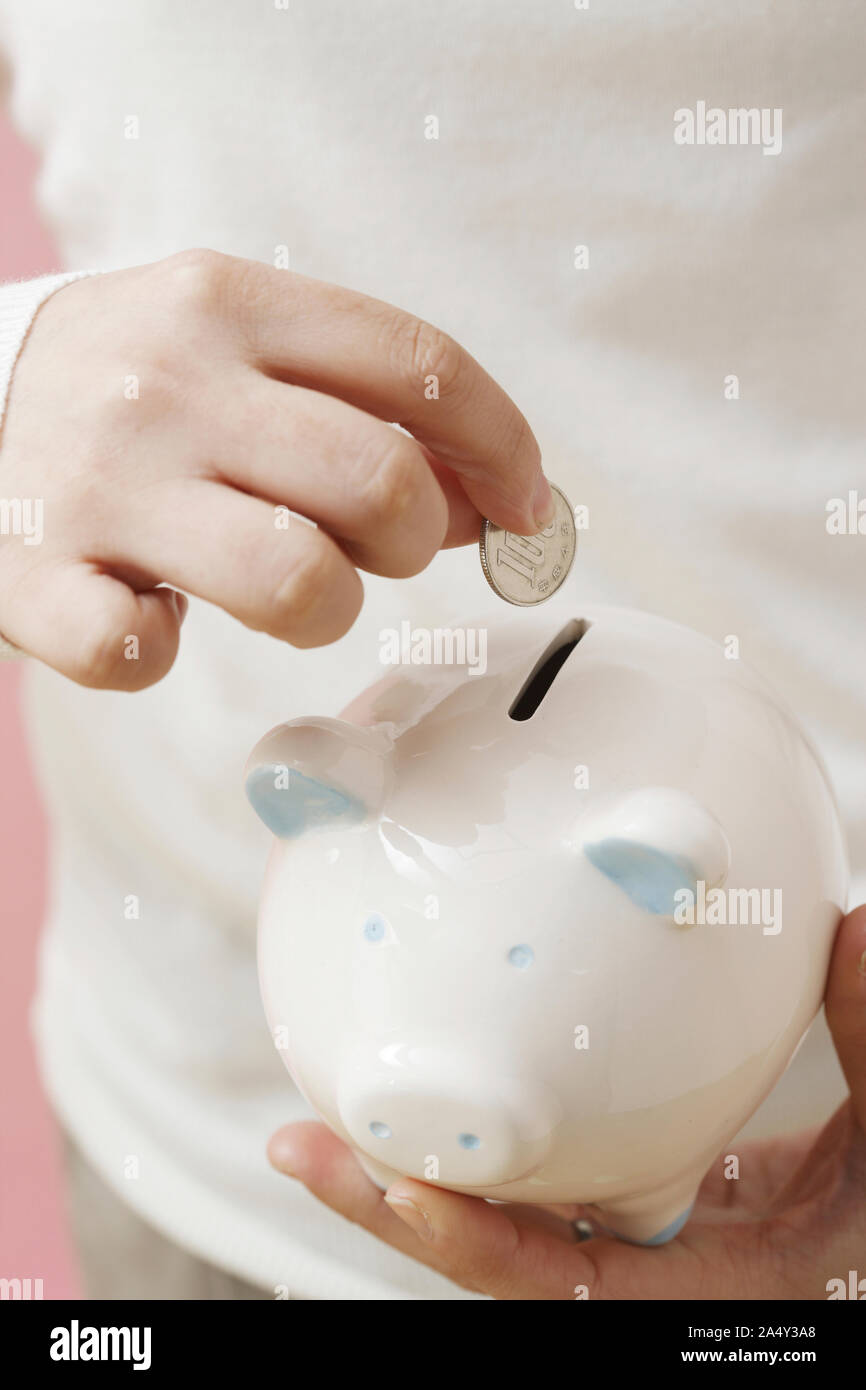 Put coins into piggy bank Stock Photo - Alamy