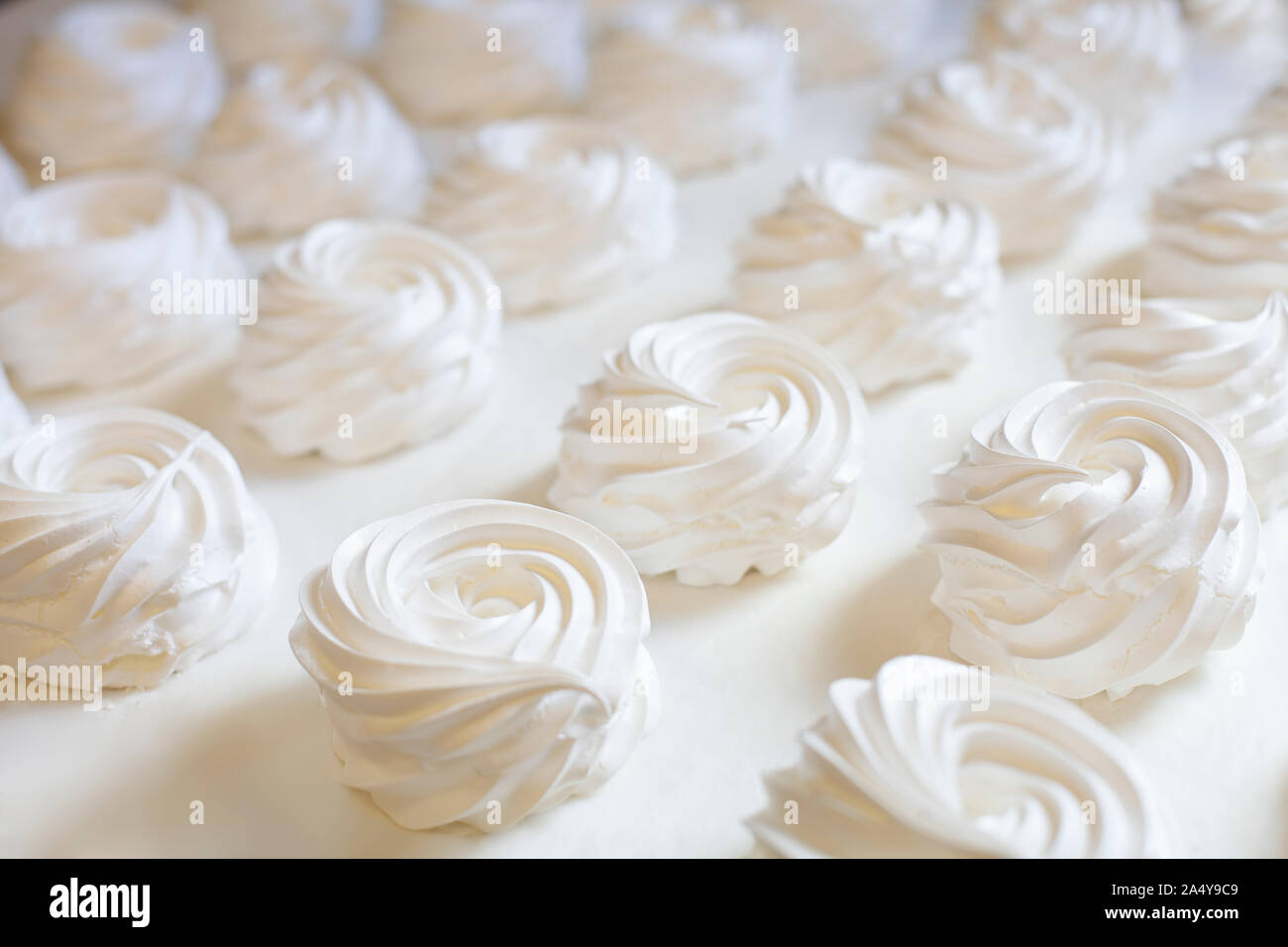 Preparation of a white meringue cake Pavlova. Meringue swirls on a ...