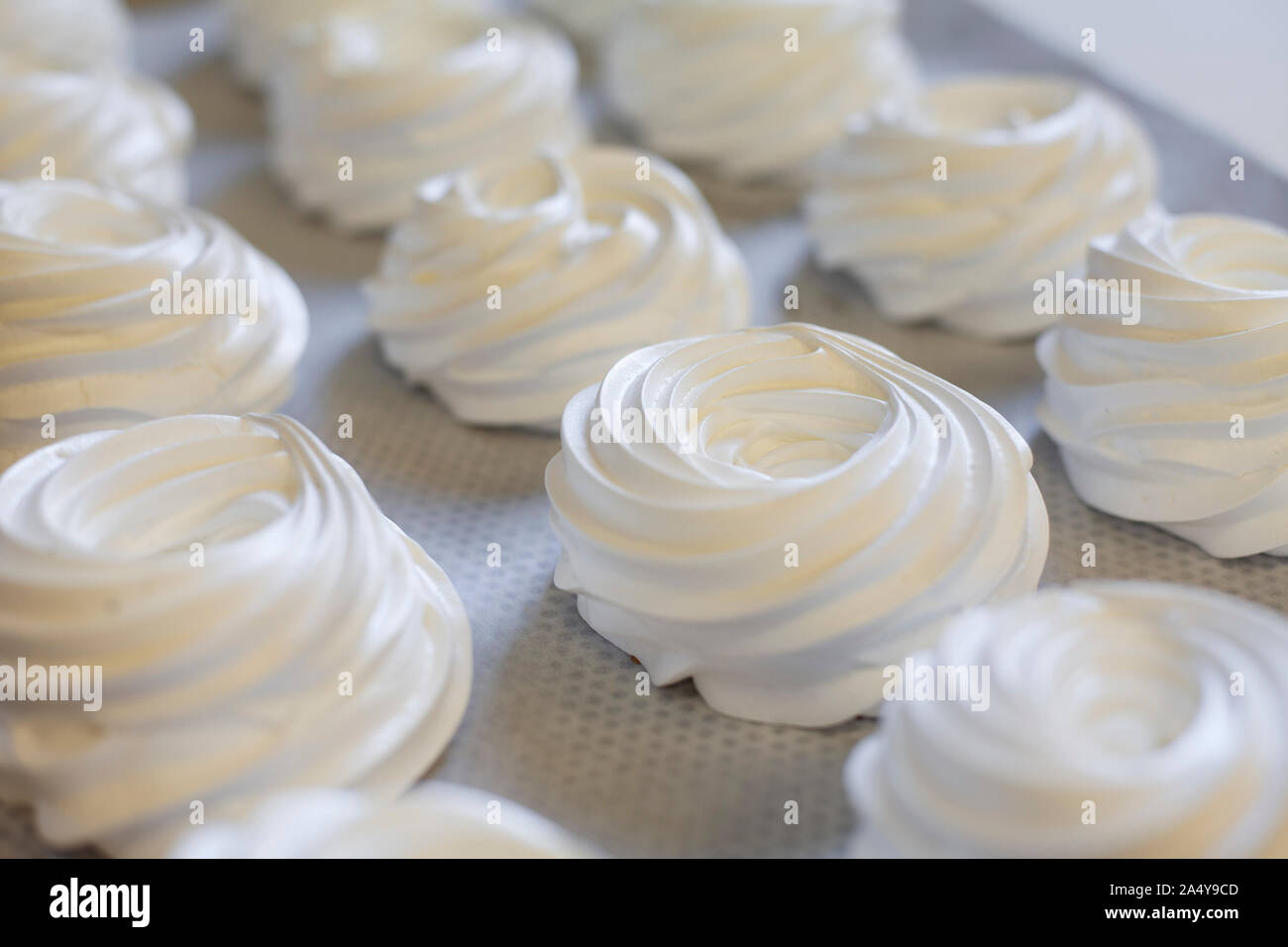 Preparation of a white meringue cake Pavlova. Meringue swirls on a ...