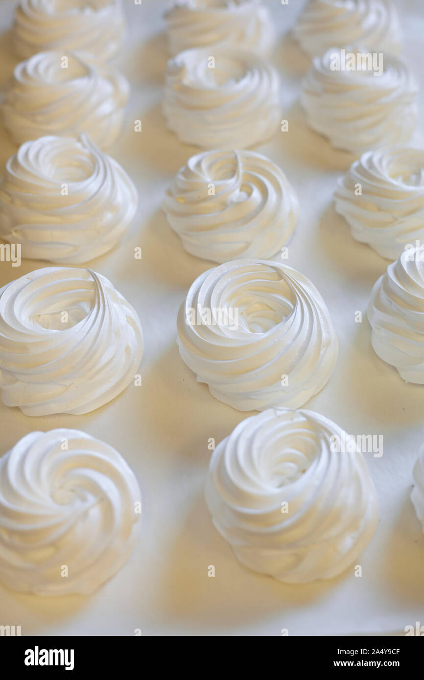 Preparation of a white meringue cake Pavlova. Meringue swirls on a ...