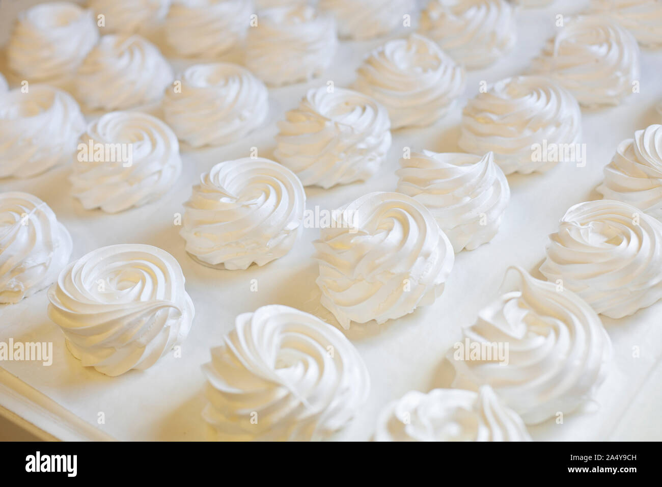 Preparation of a white meringue cake Pavlova. Meringue swirls on a ...