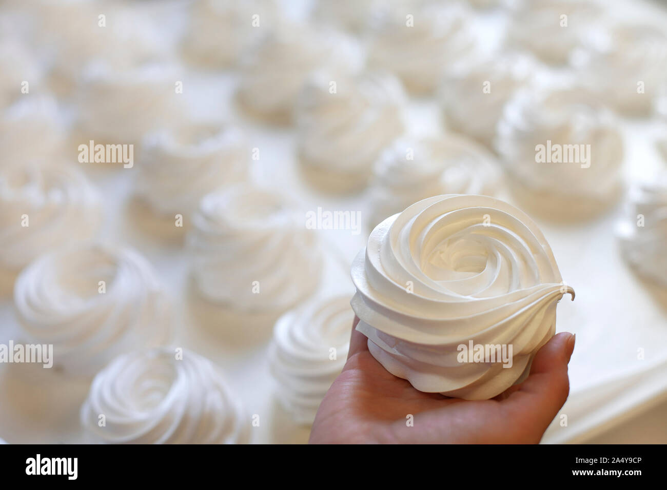 Preparation of a white meringue cake Pavlova. Meringue swirls on a ...
