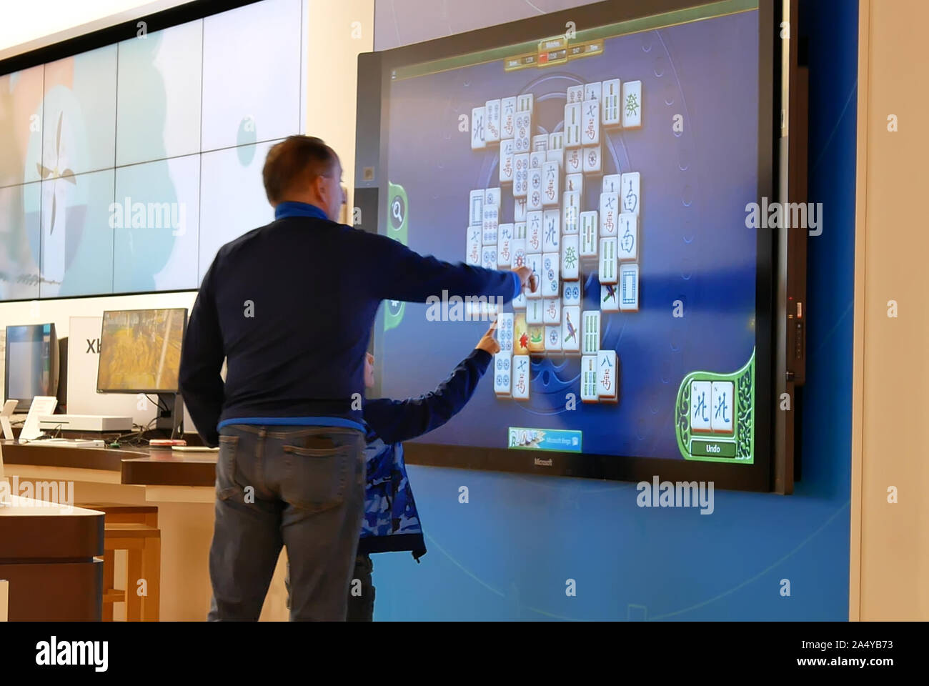 Motion of father and children playing xbox game on tv screen at ...