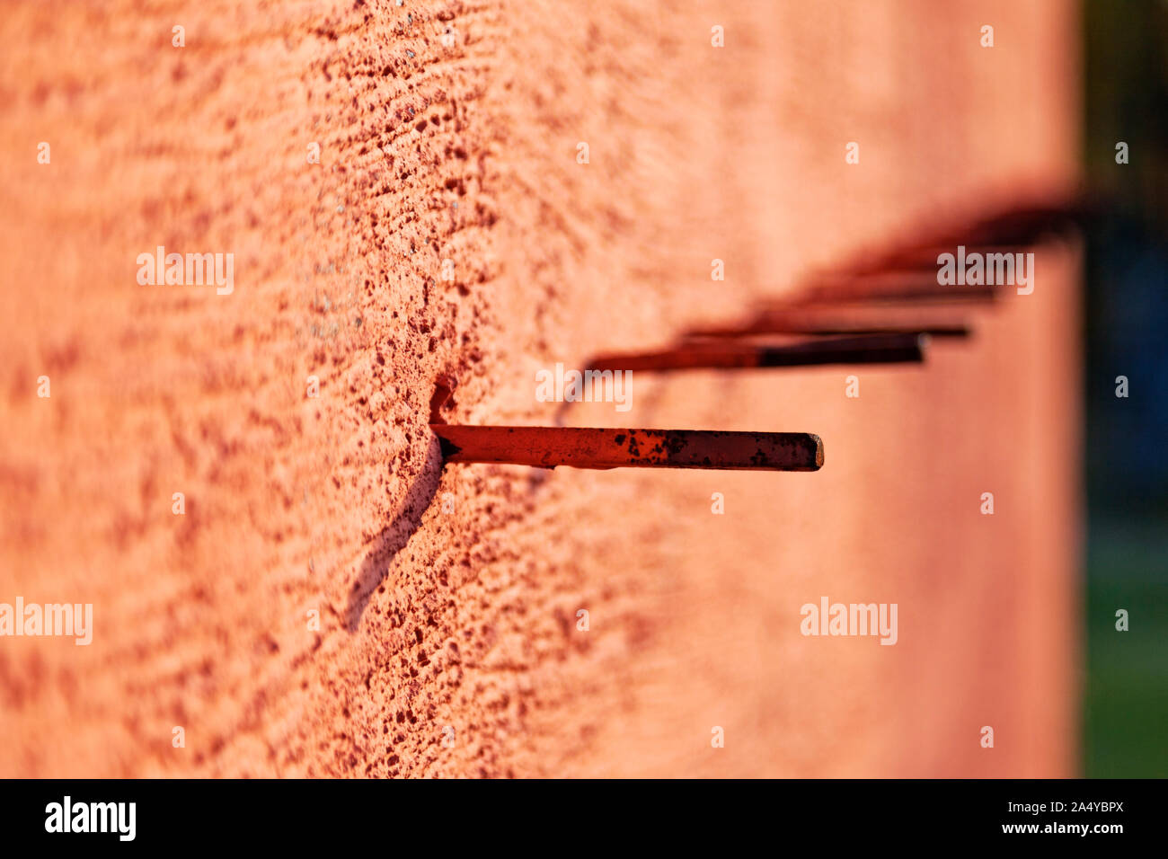 a row of metal sticks protruding from the orange concrete wall may be ...
