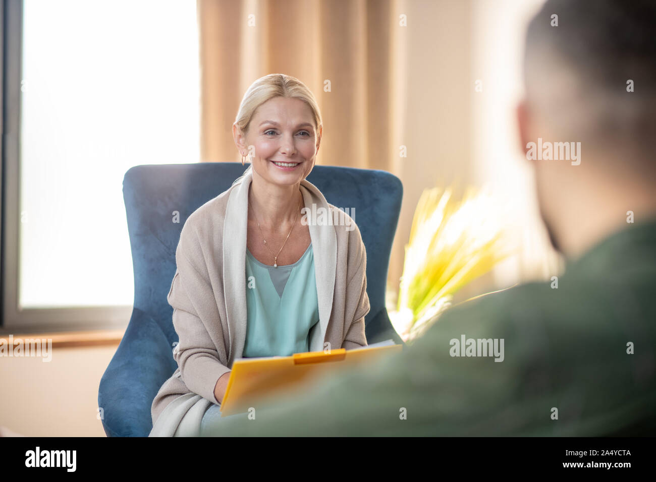 Beautiful psychoanalyst smiling while talking to client Stock Photo - Alamy