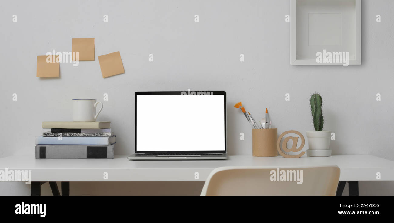 Open blank screen laptop computer in minimal workplace with painting ...