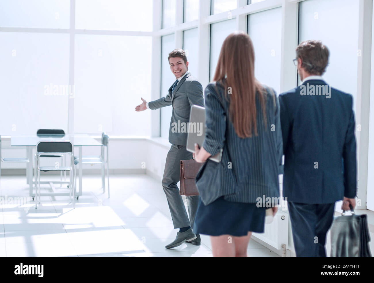 young businessman inviting employees to his new office Stock Photo - Alamy