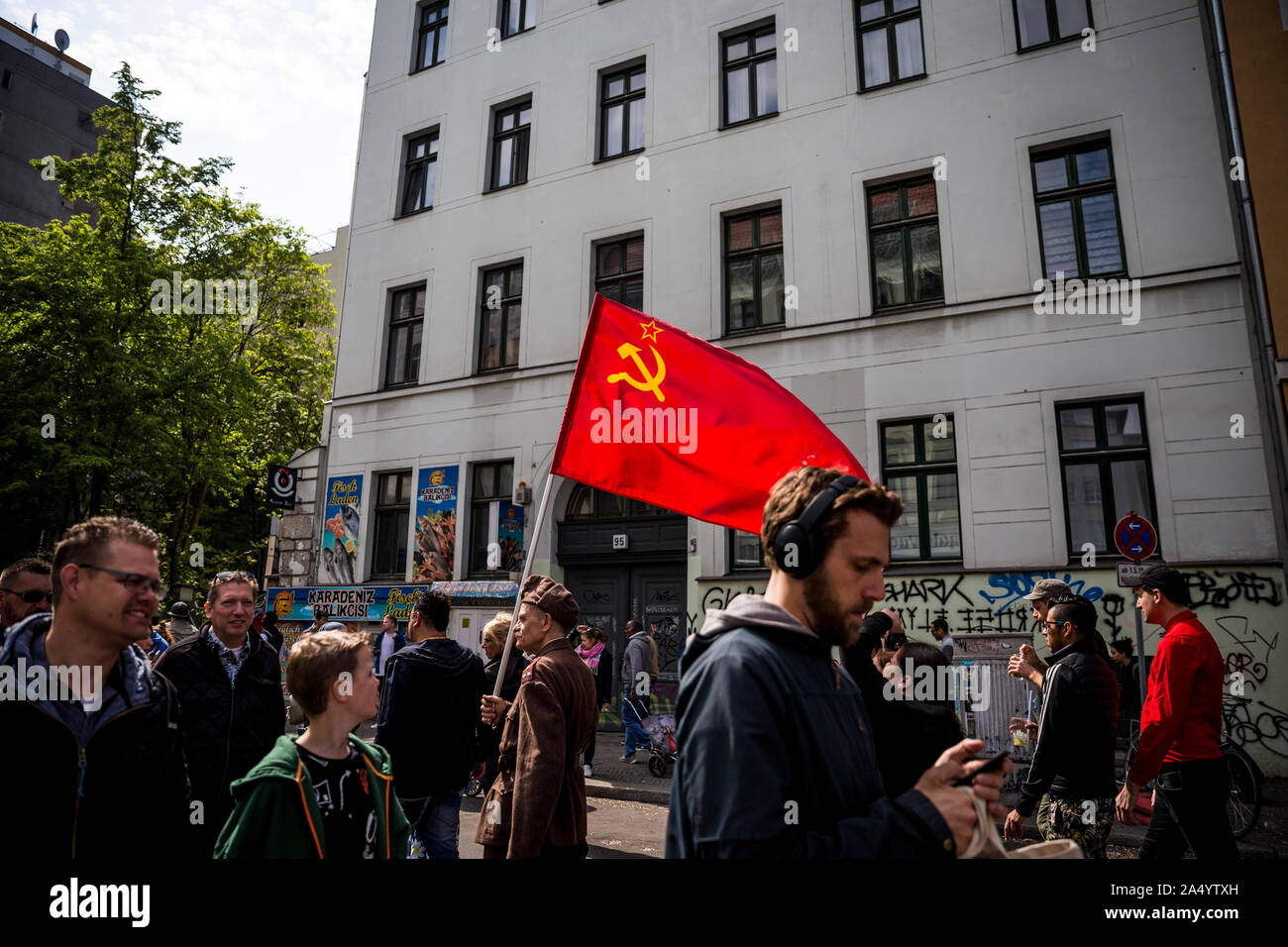An elderly man in military uniform carries a communist flag on May Day ...