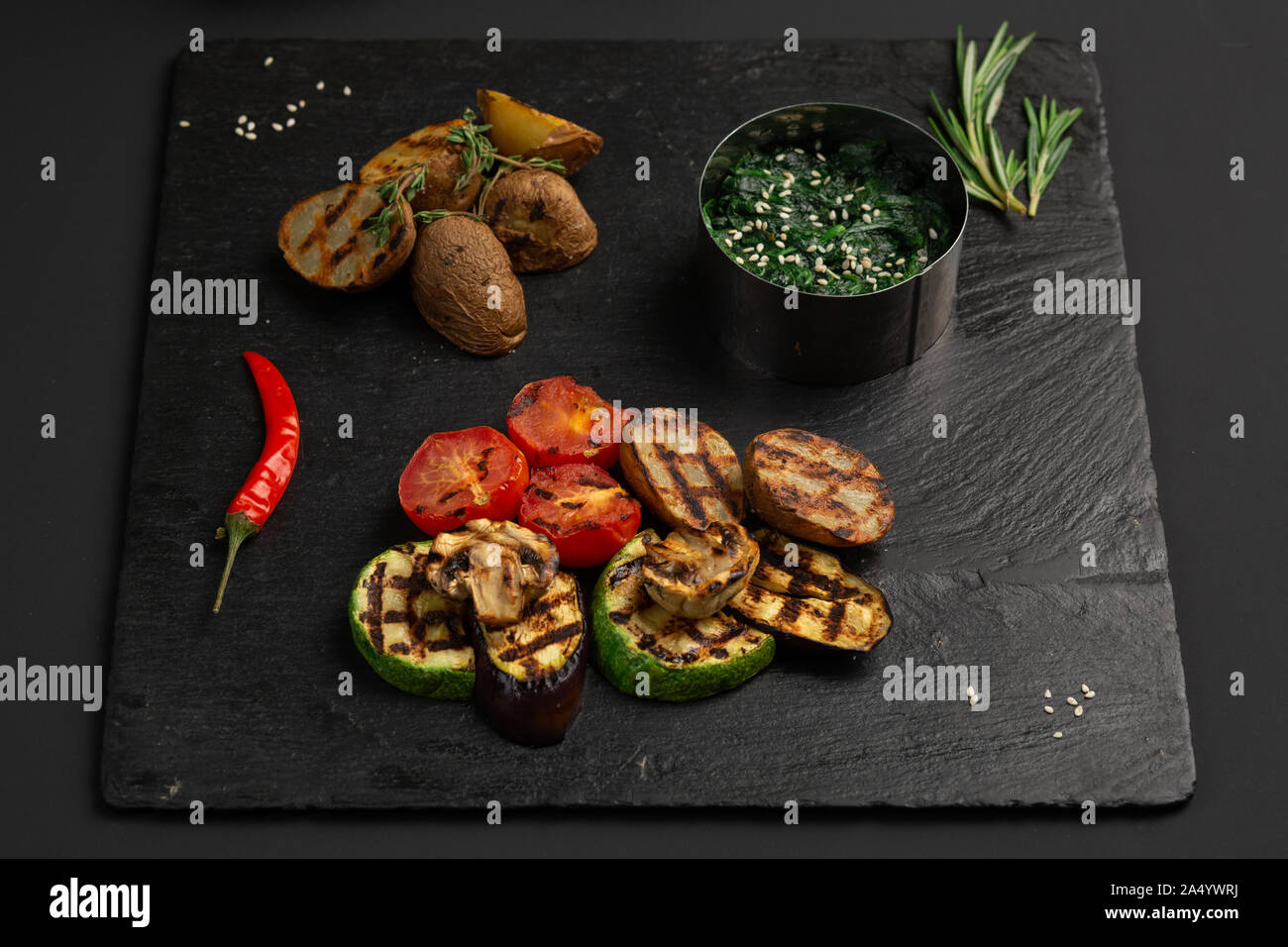 chuka salad and baked vegetables on a black board decorated with pepper ...