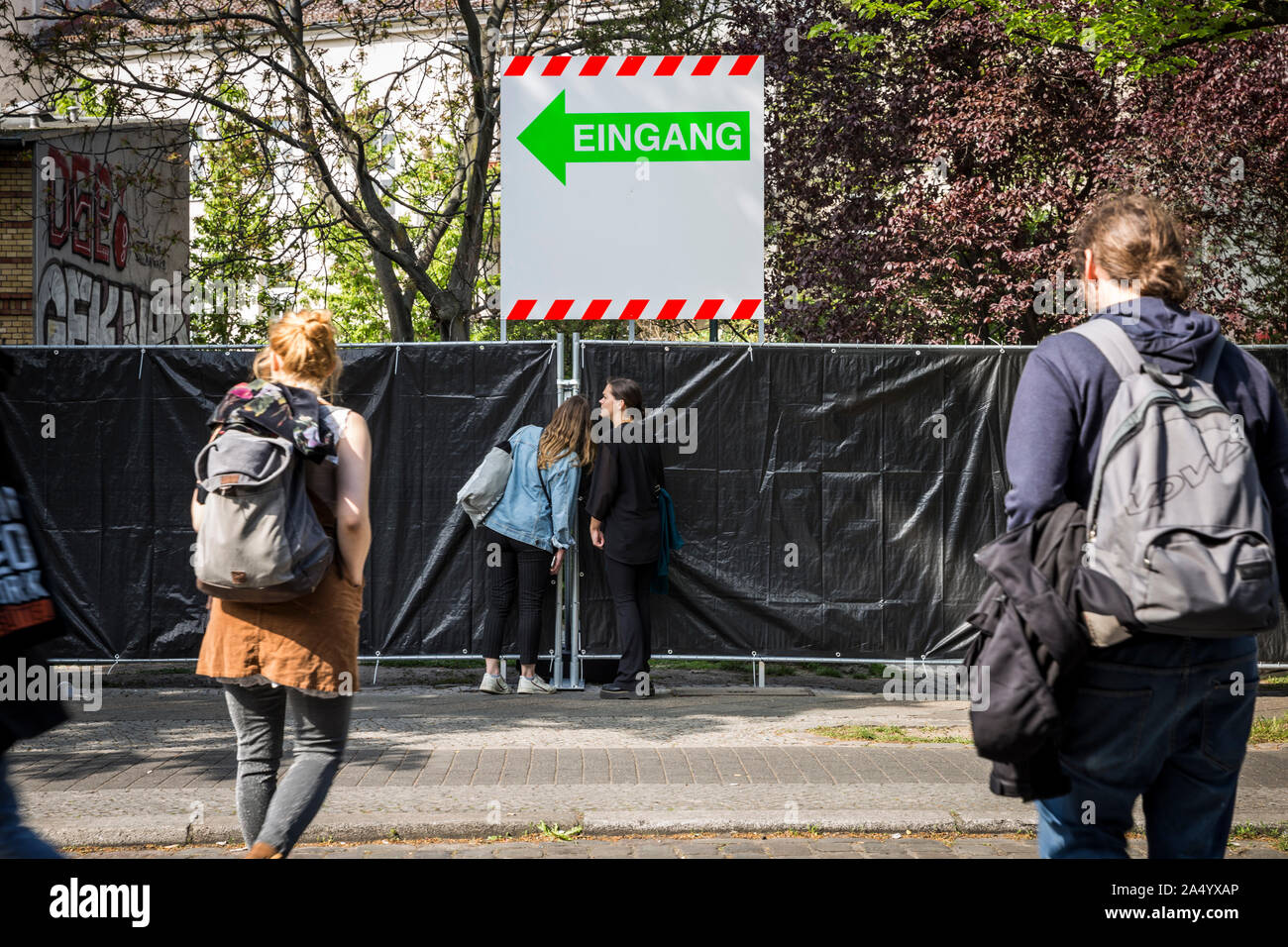 Women peer through a gap in a fence on May Day 2019 in Berlin, Germany ...