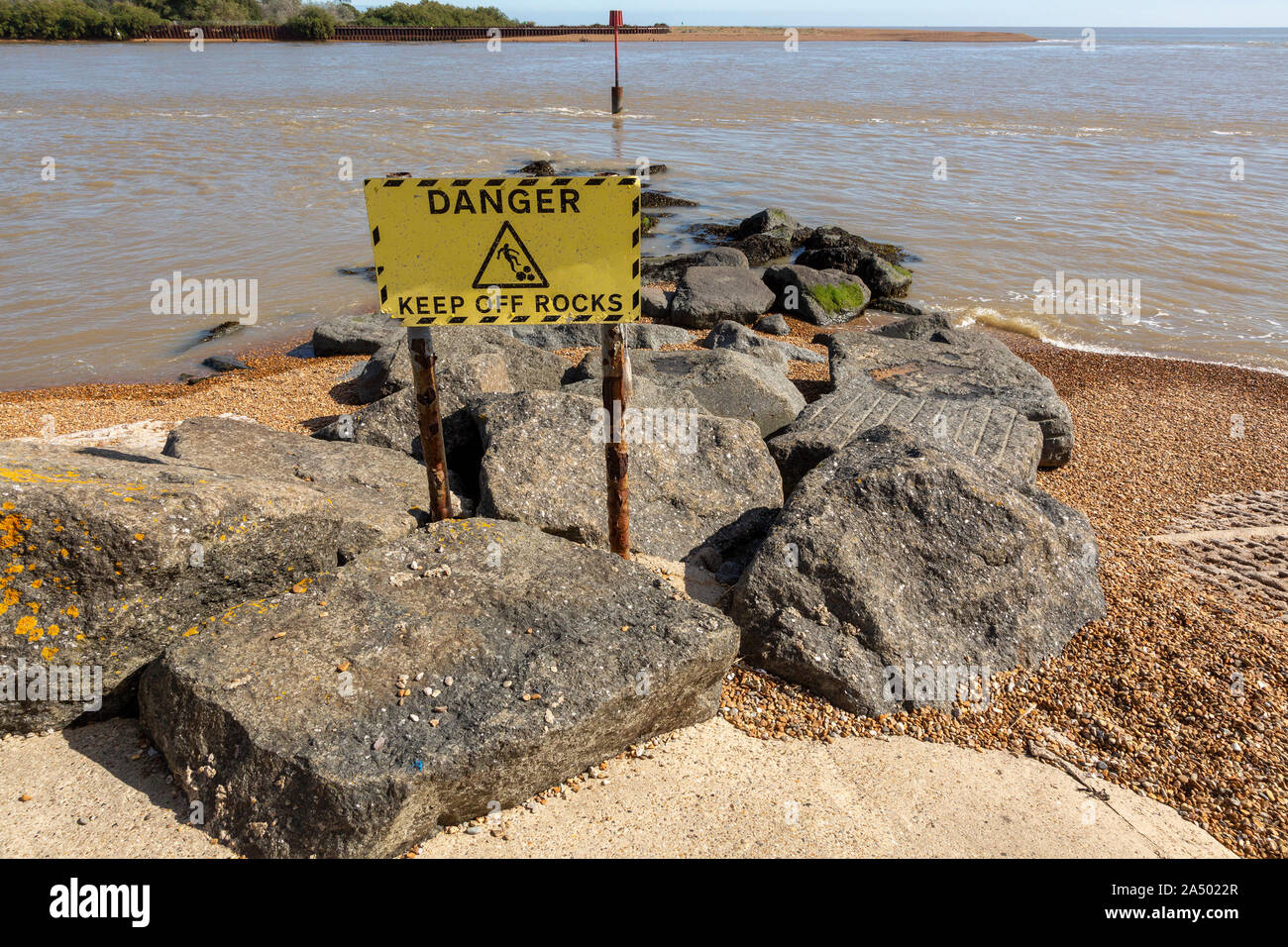 Danger Keep off Rocks sign on rock armour groyne, mouth of River Deben ...