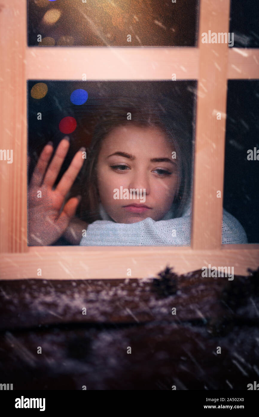 lonely and sad girl looks out the window in winter evening Stock Photo ...