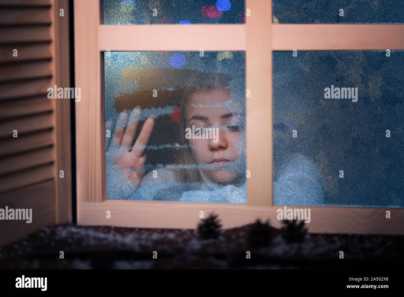 lonely and sad girl looks out the window in winter evening Stock Photo ...