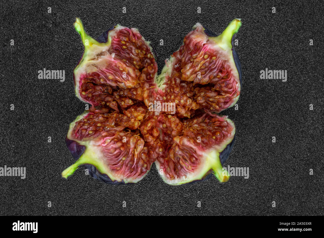 Top view of torn common fig (Ficus carica) fruit on black iron cast ...